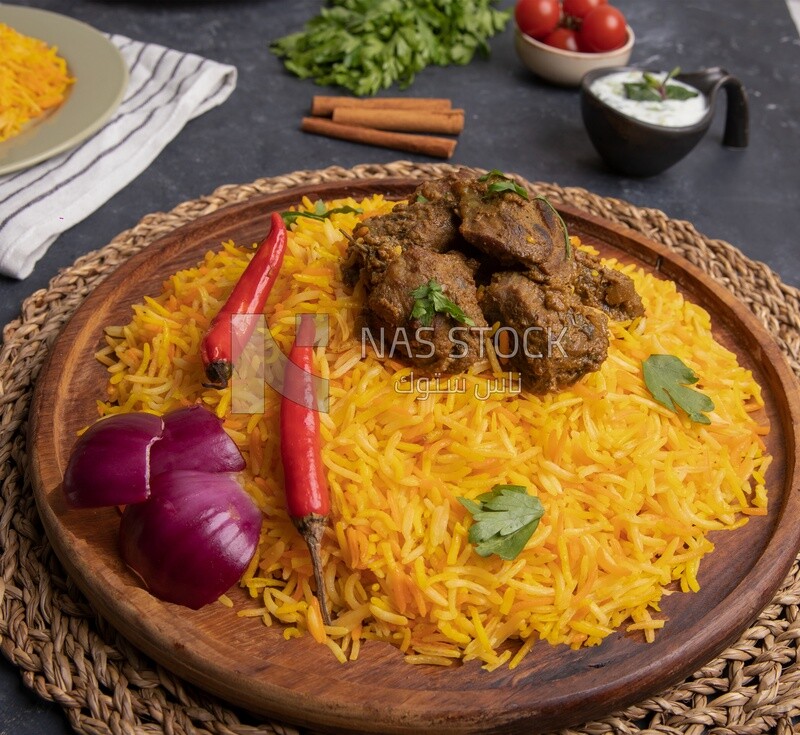 Wooden plate of delicious biryani rice with meat, traditional Arabic ...