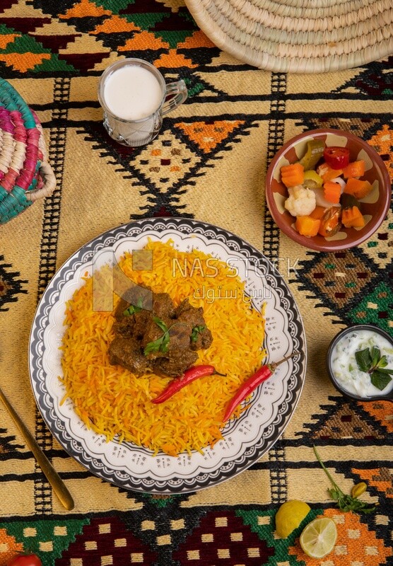 Wooden plate of delicious biryani rice with meat and a plate of dates ...