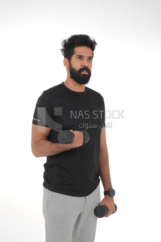 Saudi man Wearing sports clothes, exercising with dumbbells ...