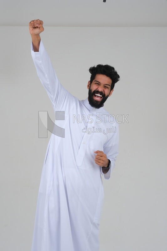 Saudi man wearing a white dress looks happy, facial gestures indicating ...