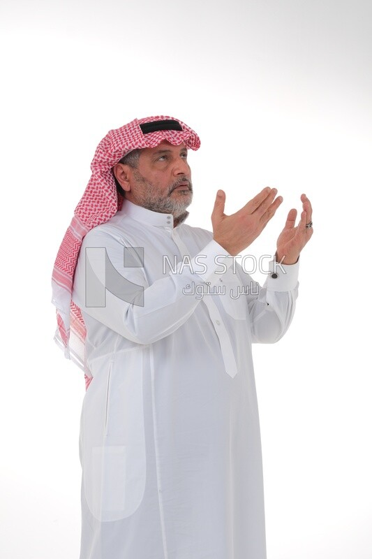 The side view of a Saudi man wearing a white dress, praying to god ...