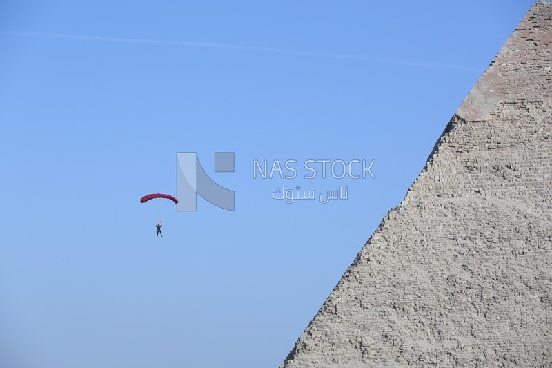 A person flying in the sky with a parachute next to the Great Pyramid ...