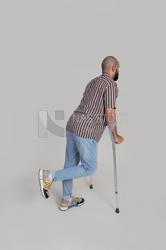 back view of a man with an injured leg walking with crutches, patient ...